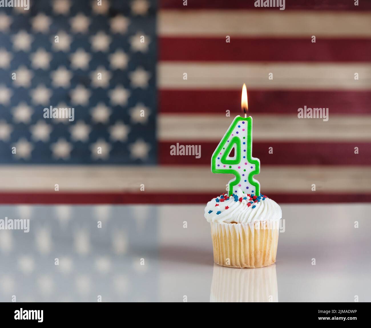 Burning number four candle inside cupcake with rustic wooden flag of ...