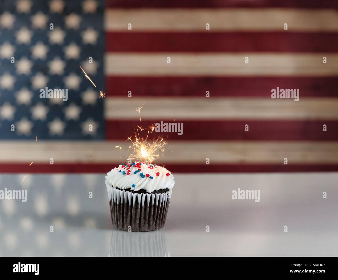 Glowing sparkler inside cupcake with rustic wooden flag of United ...