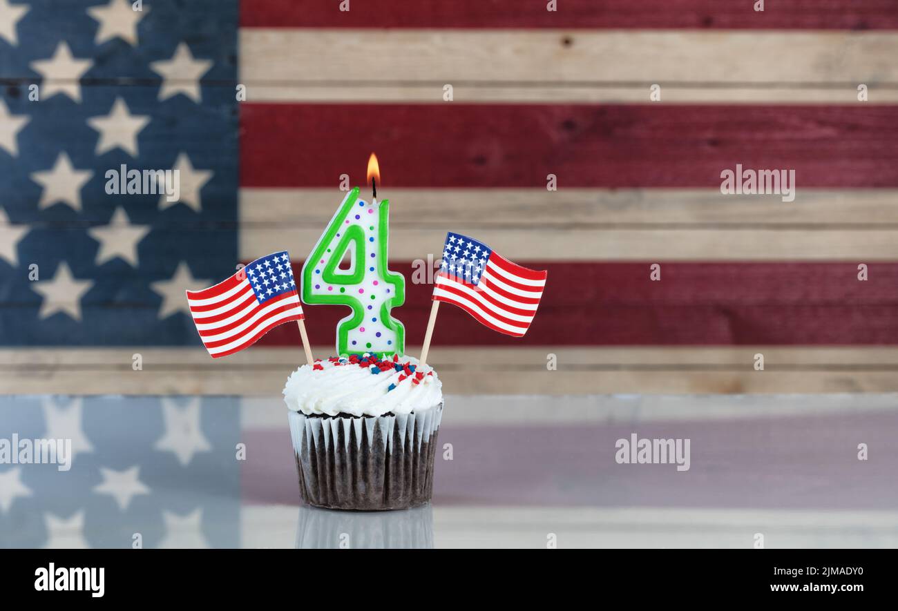 Burning number four candle and small USA flags inside cupcake with ...