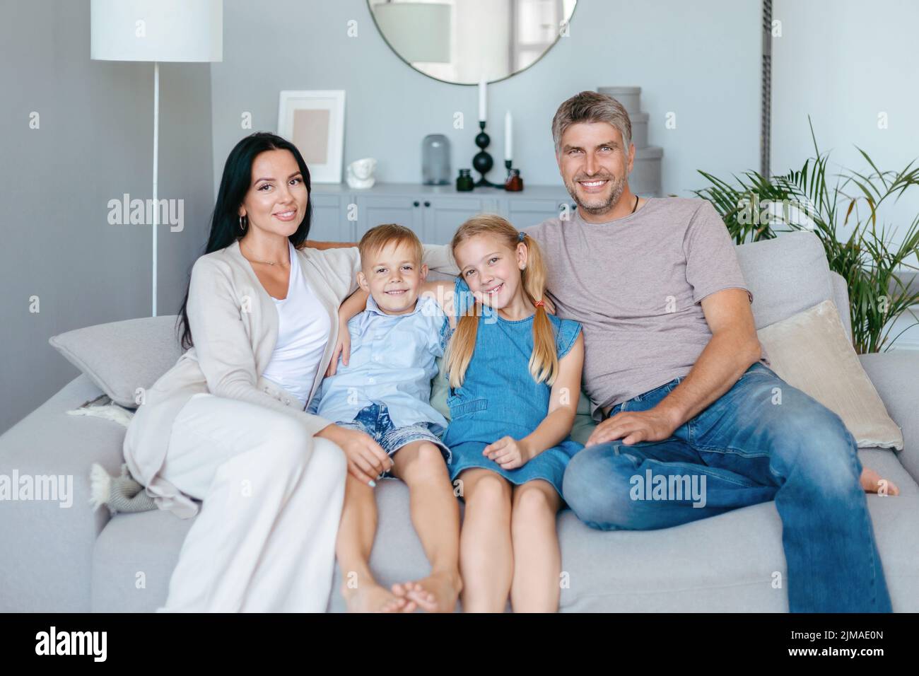 parents with two children sitting on a comfortable sofa Stock Photo - Alamy