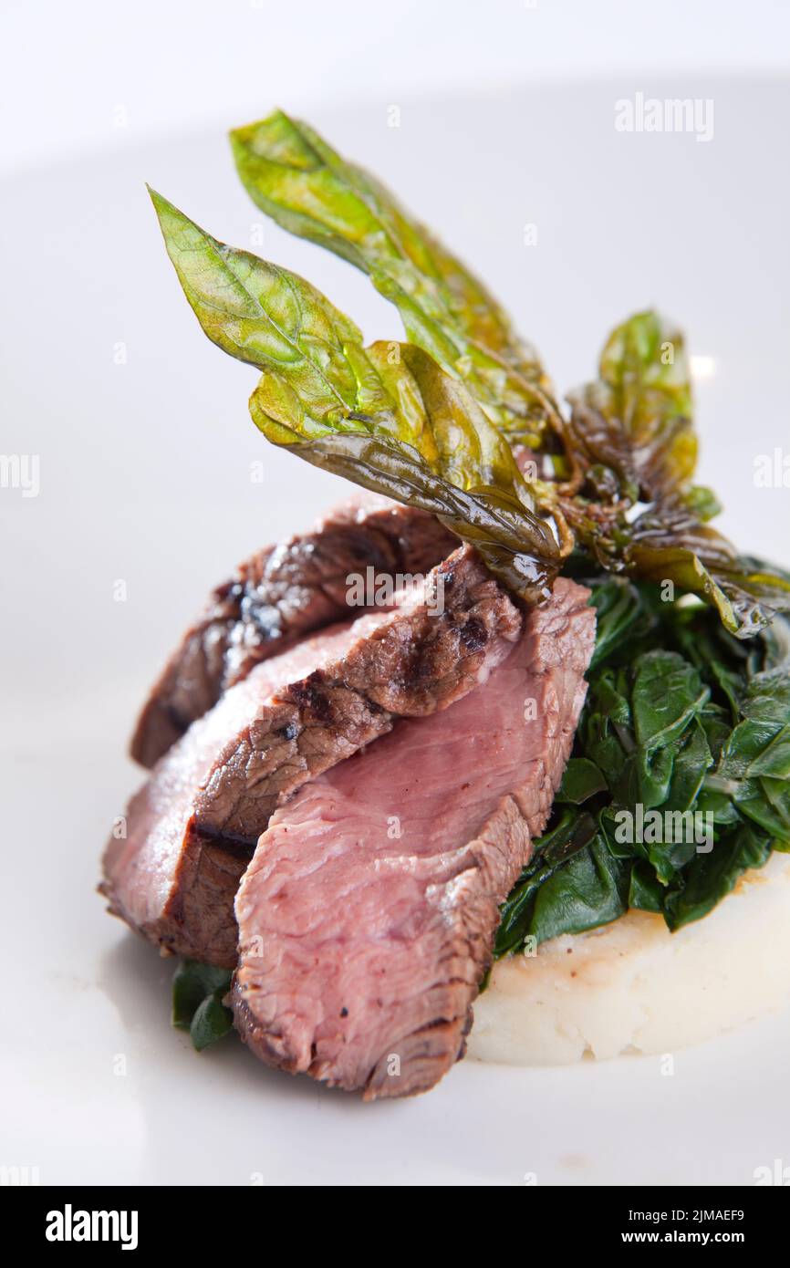 Grilled beef fillet topped with deep-fried basil, on spinach Stock ...