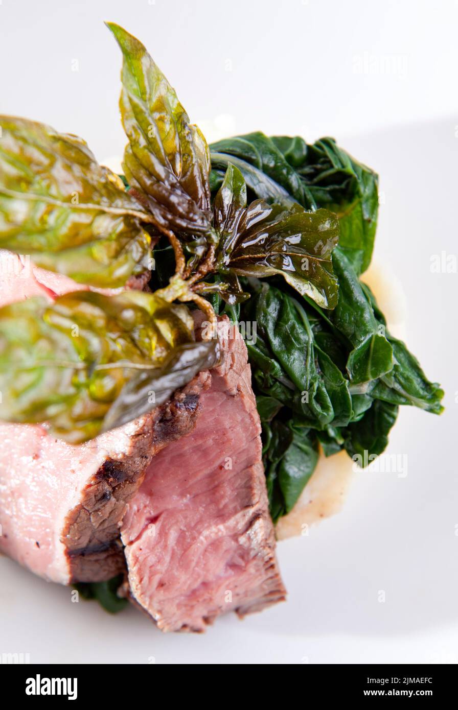 Grilled beef fillet topped with deep-fried basil, on spinach Stock ...