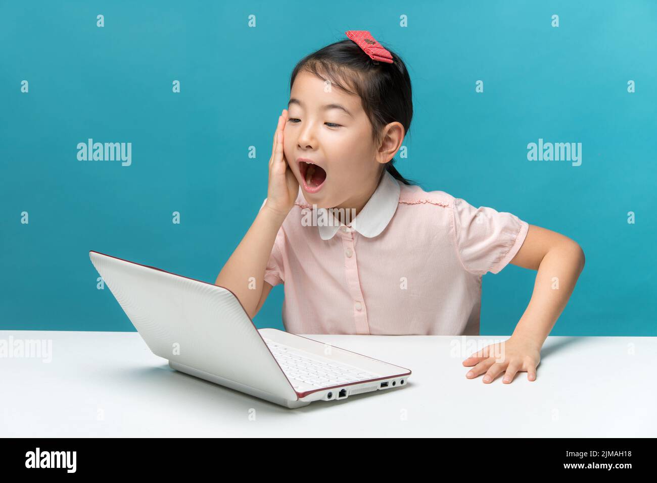 Surprised, Cute asia little girl who enjoy the laptop computer on blue ...