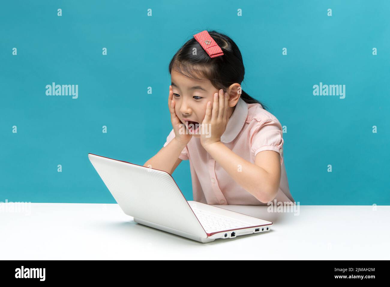 Surprised, Cute asia little girl who enjoy the laptop computer on blue ...