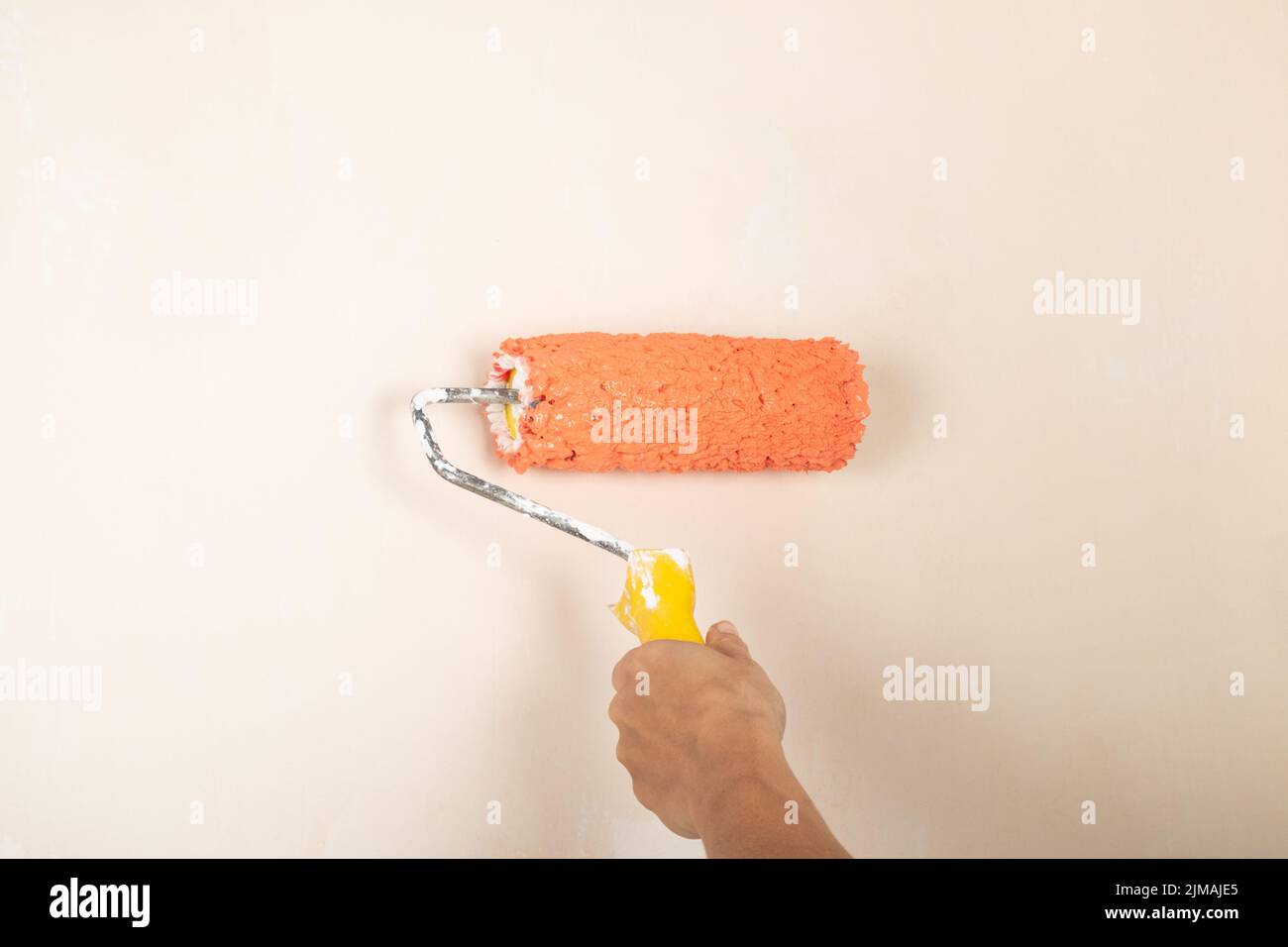paint roller in the worker's hand on the background of the wall Stock ...