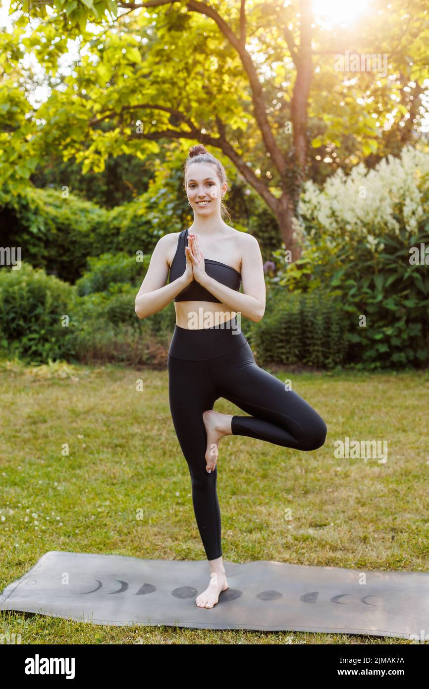 Young smiling woman practice yoga tree - vrikshasana pose in sunset ...