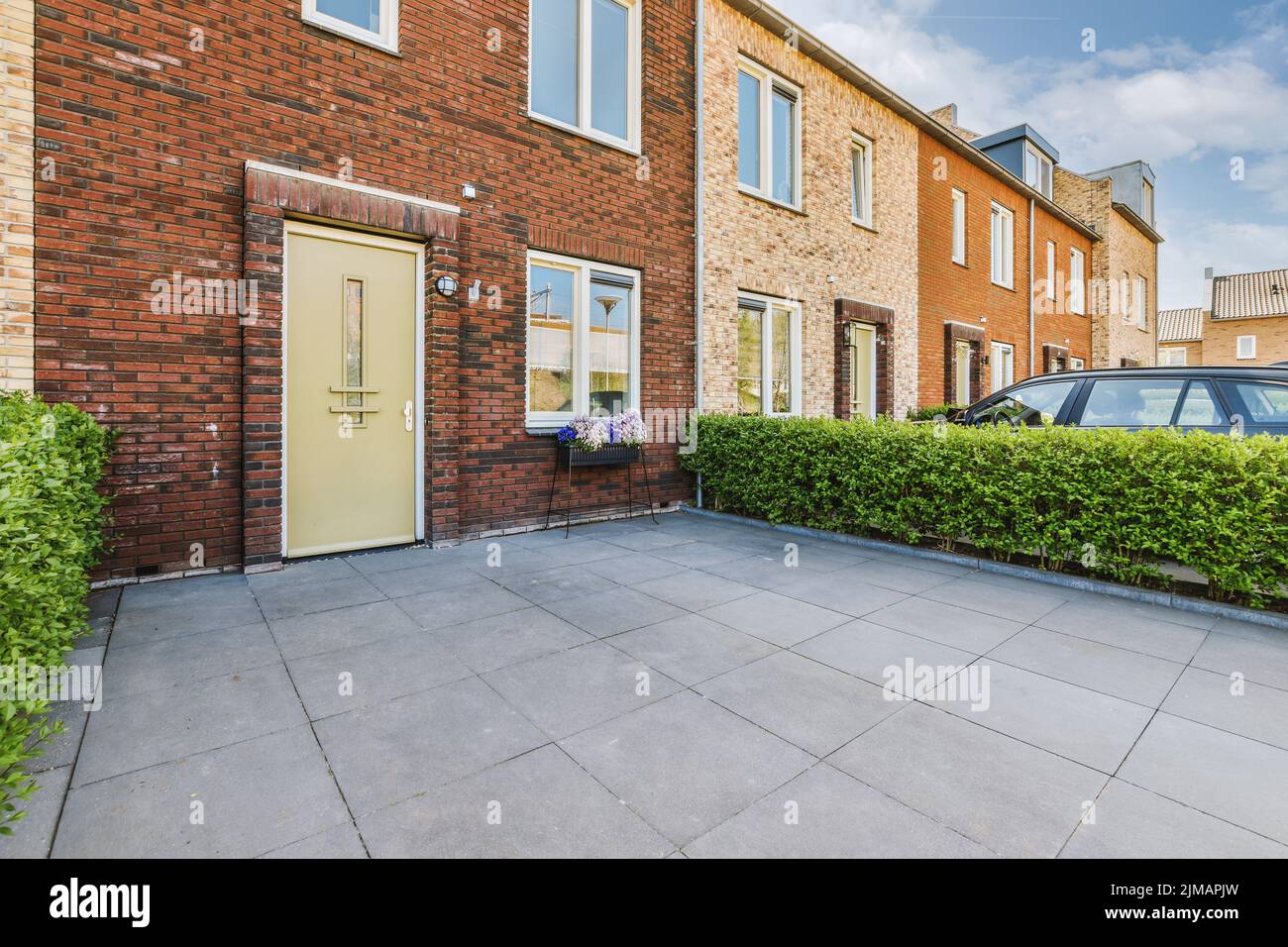 The front view of a brick building with signs, cars, pavement and ...