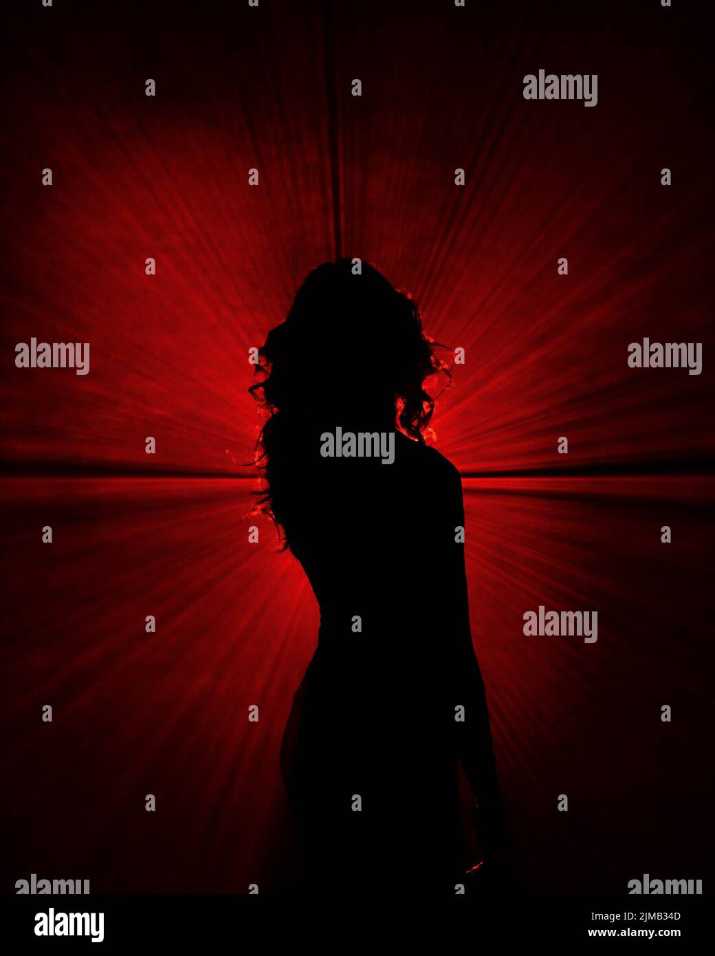A vertical shot of a graceful woman silhouette under the red light ...