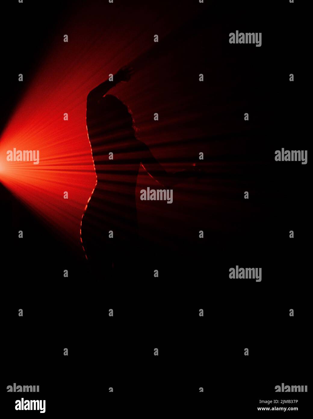 A vertical shot of a graceful dancing woman silhouette under the red ...