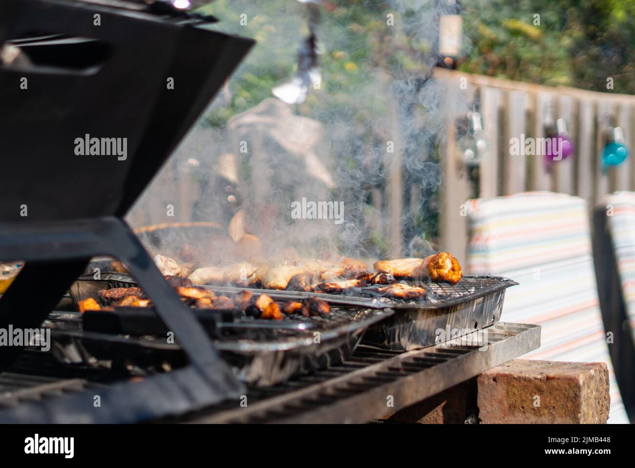 A closeup view of grill chicken meat over hot coals in BBQ at campsite ...