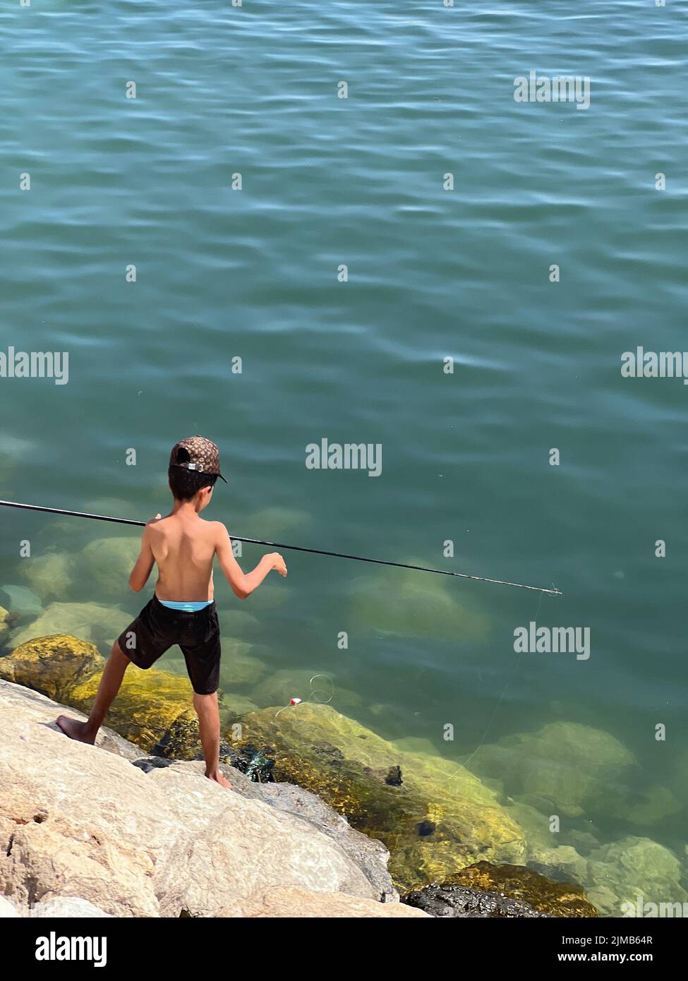 A Young boy fishing on the mediterranean sea Stock Photo - Alamy