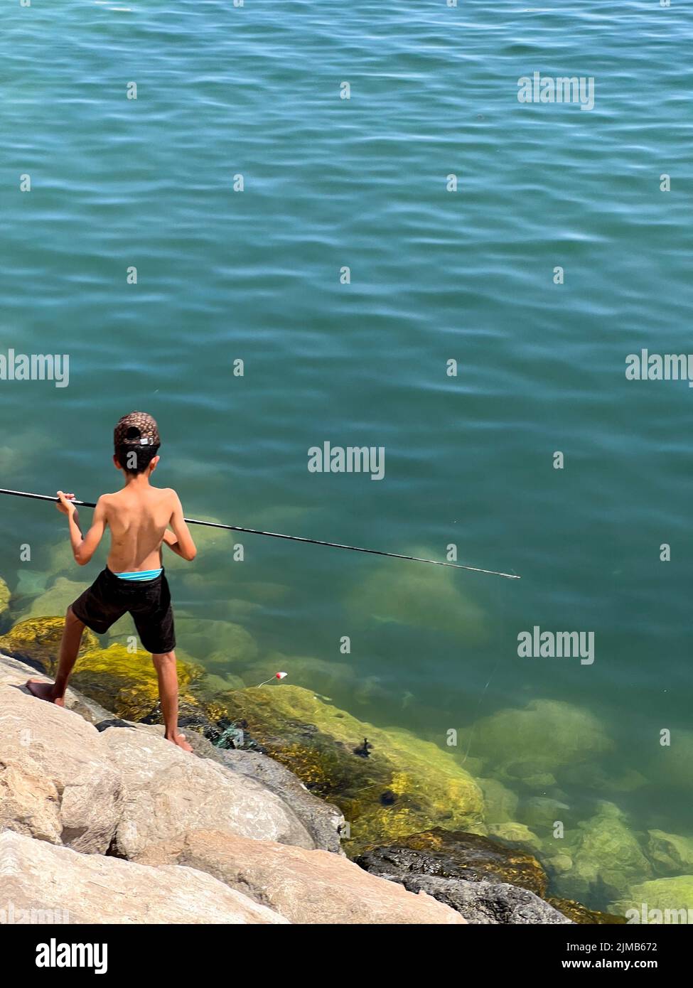 A Young boy fishing on the mediterranean sea Stock Photo - Alamy
