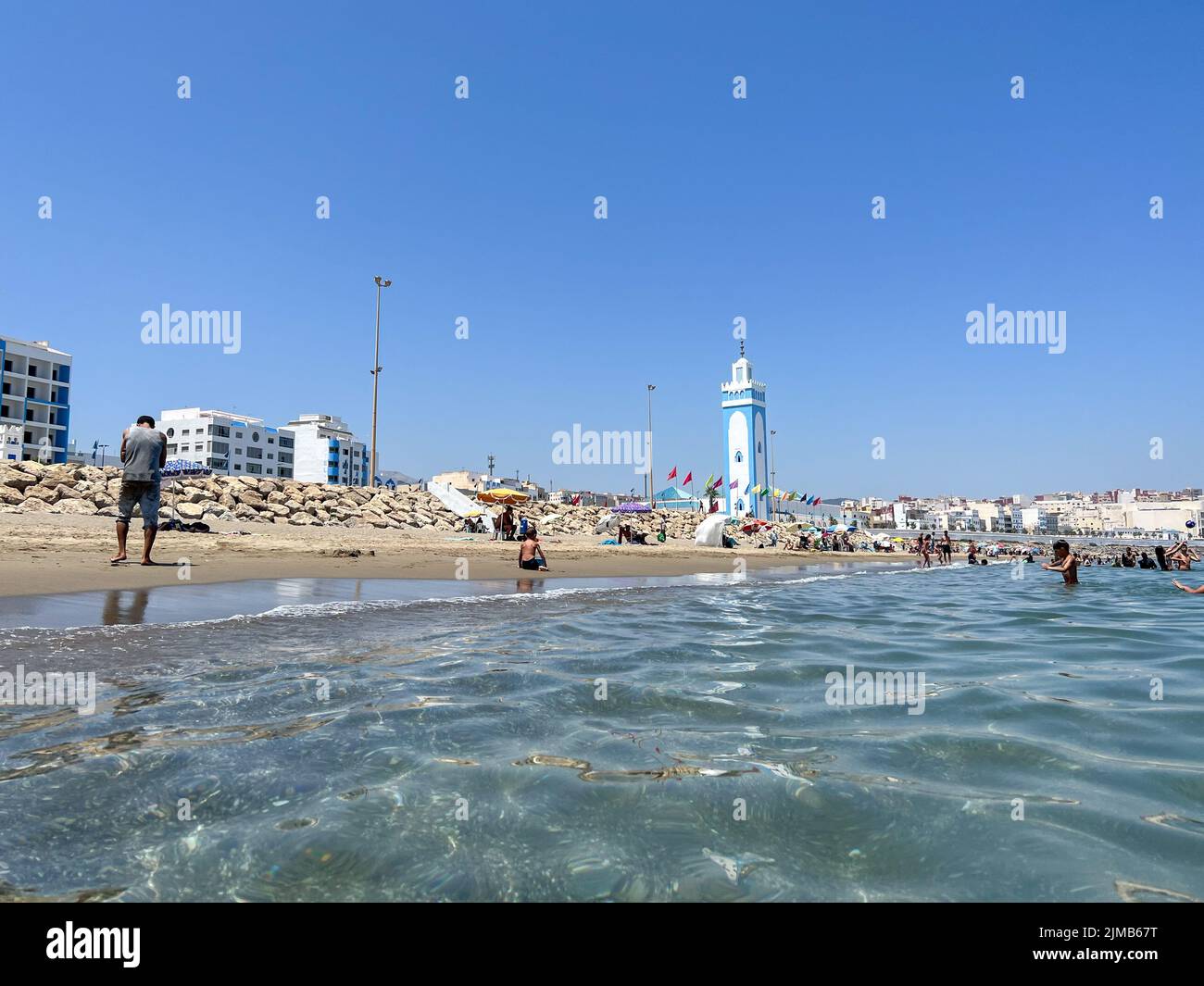 A crowd of people enjoying their summer holiday on the beach nearby ...
