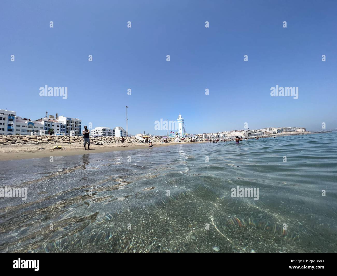 A crowd of people enjoying their summer holiday on the beach nearby ...