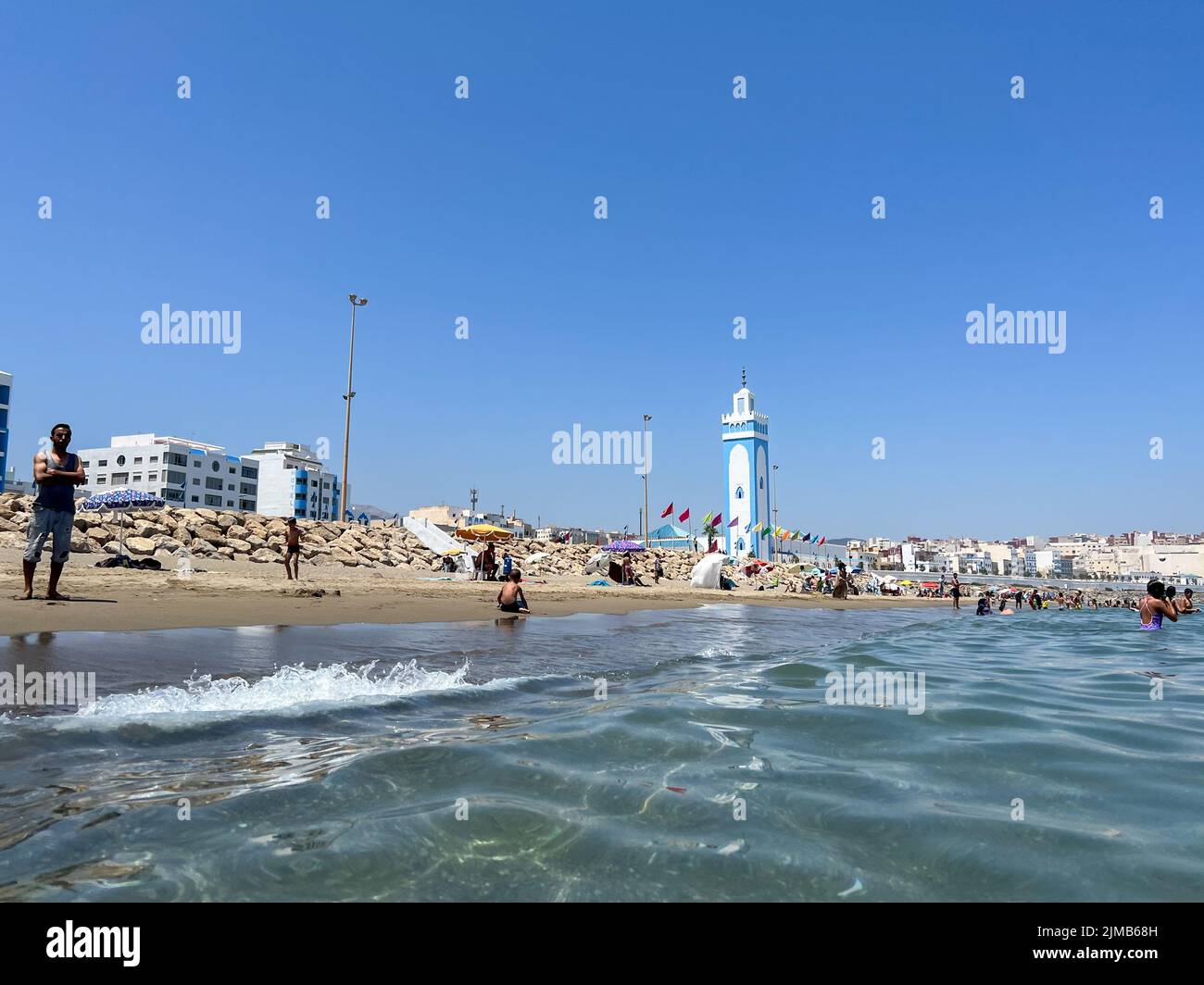 A crowd of people enjoying their summer holiday on the beach nearby ...