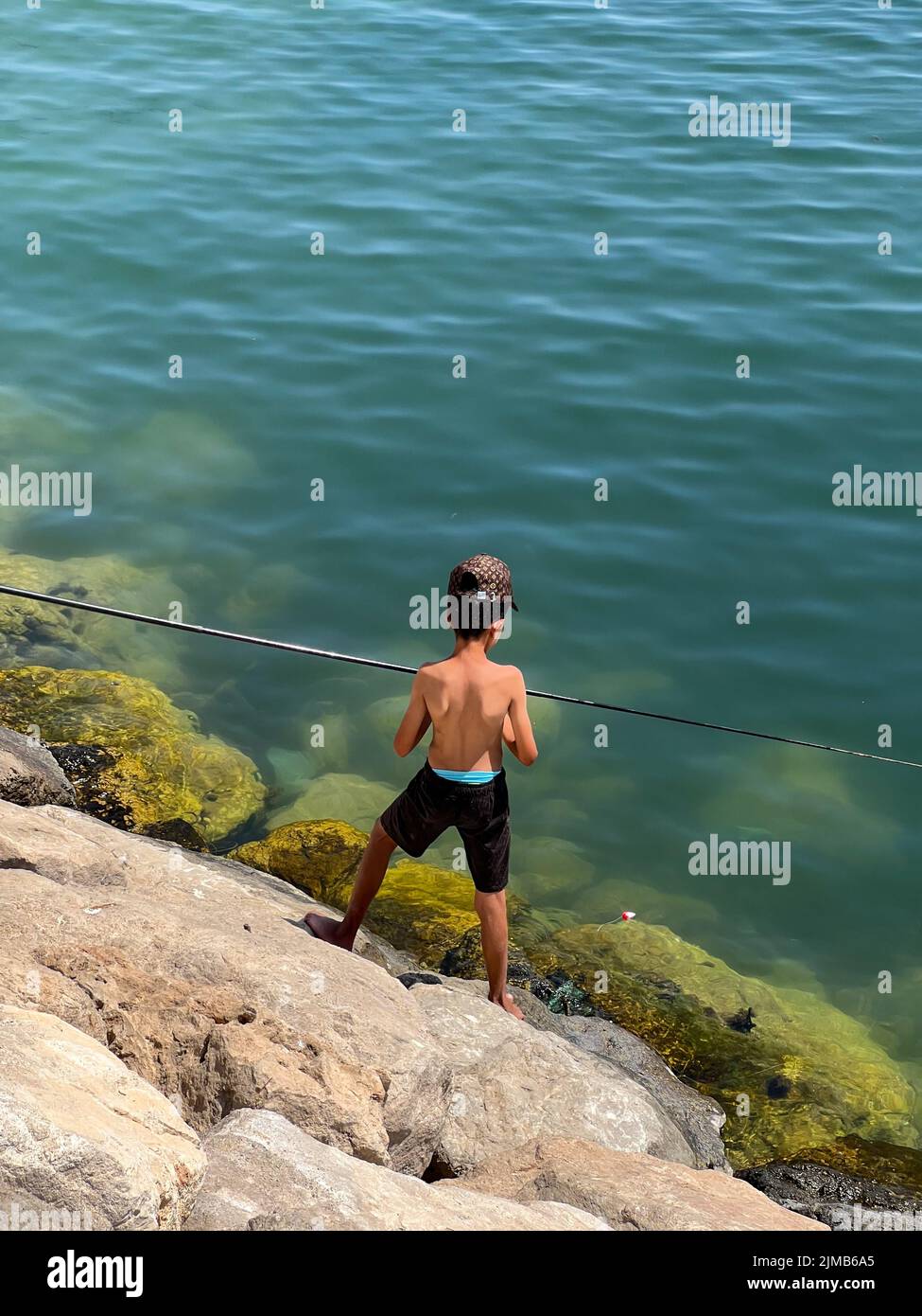 A Young boy fishing on the mediterranean sea Stock Photo - Alamy