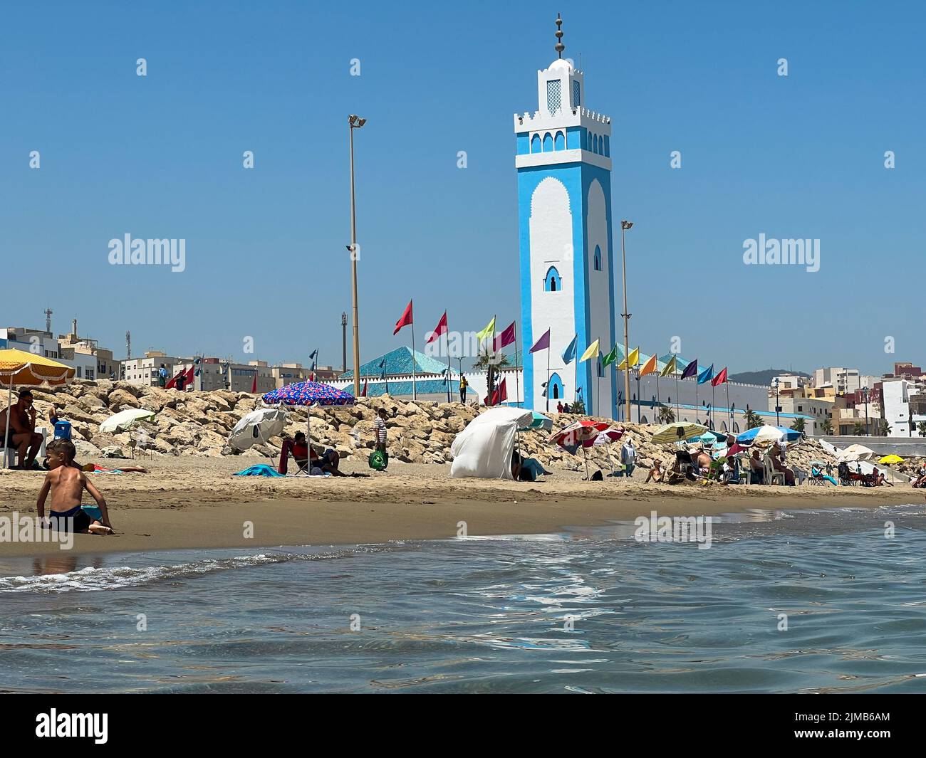A crowd of people enjoying their summer holiday on the beach nearby ...