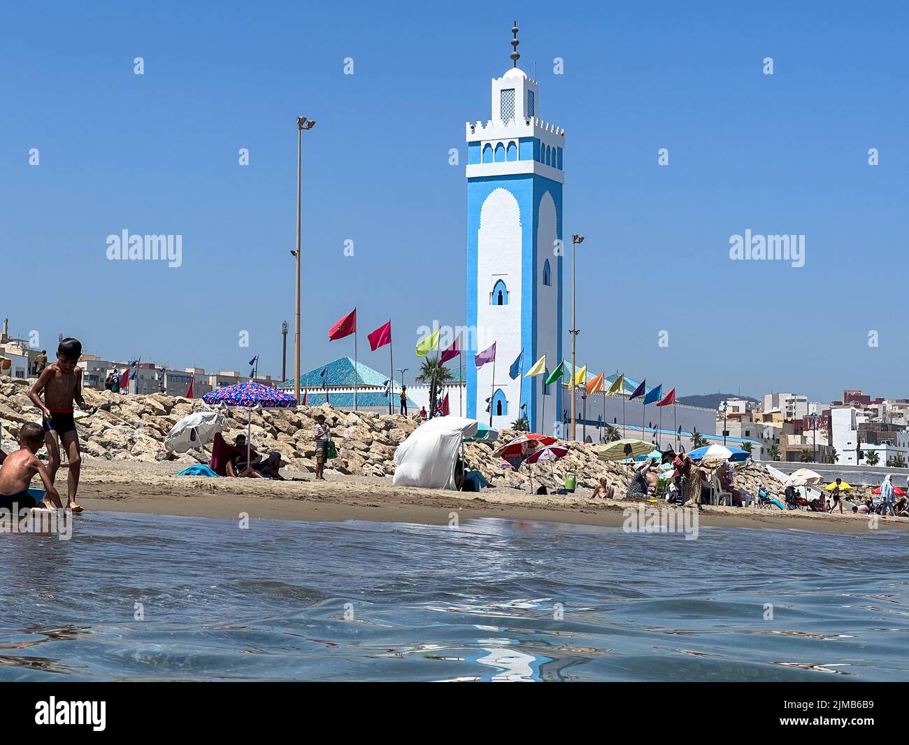 A crowd of people enjoying their summer holiday on the beach nearby ...