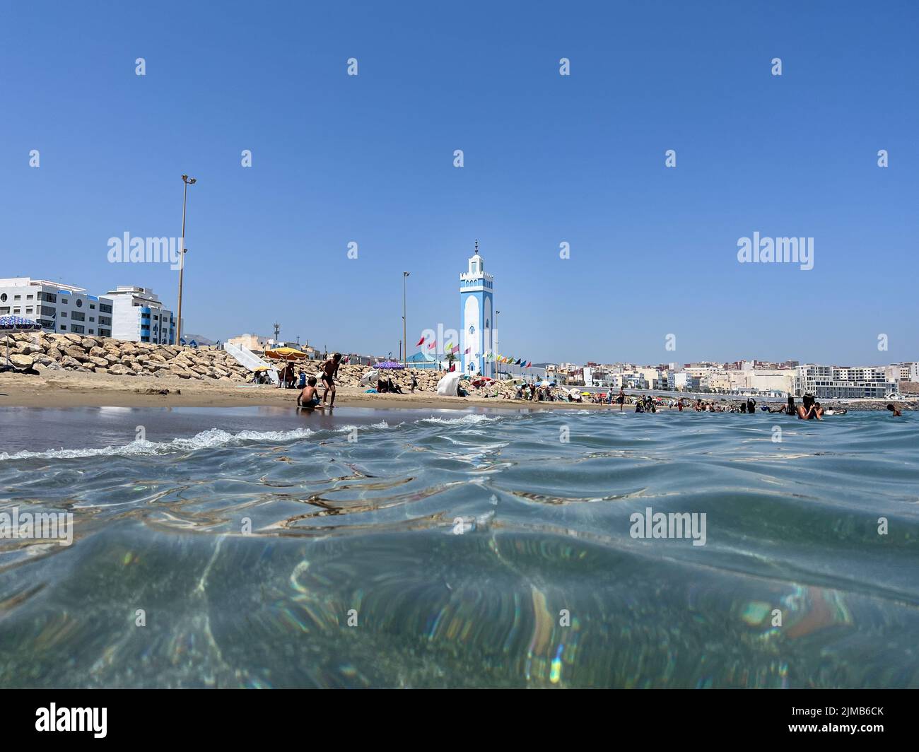 A crowd of people enjoying their summer holiday on the beach nearby ...