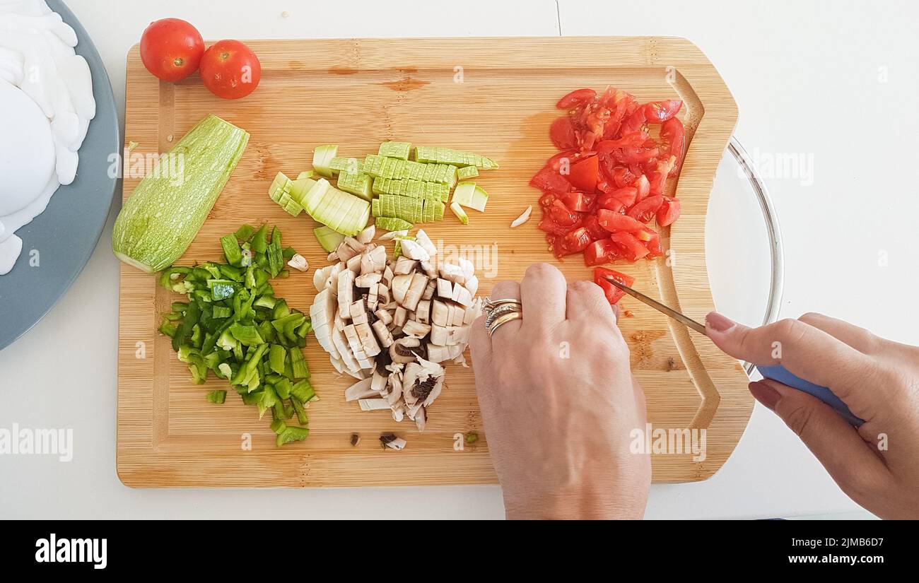 Top down view on chopping board with hands slicing vegetables Stock Photo - Alamy