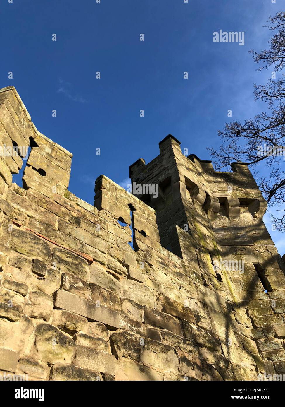 A low angle shot of an antique stone wall of a castle against a blue ...