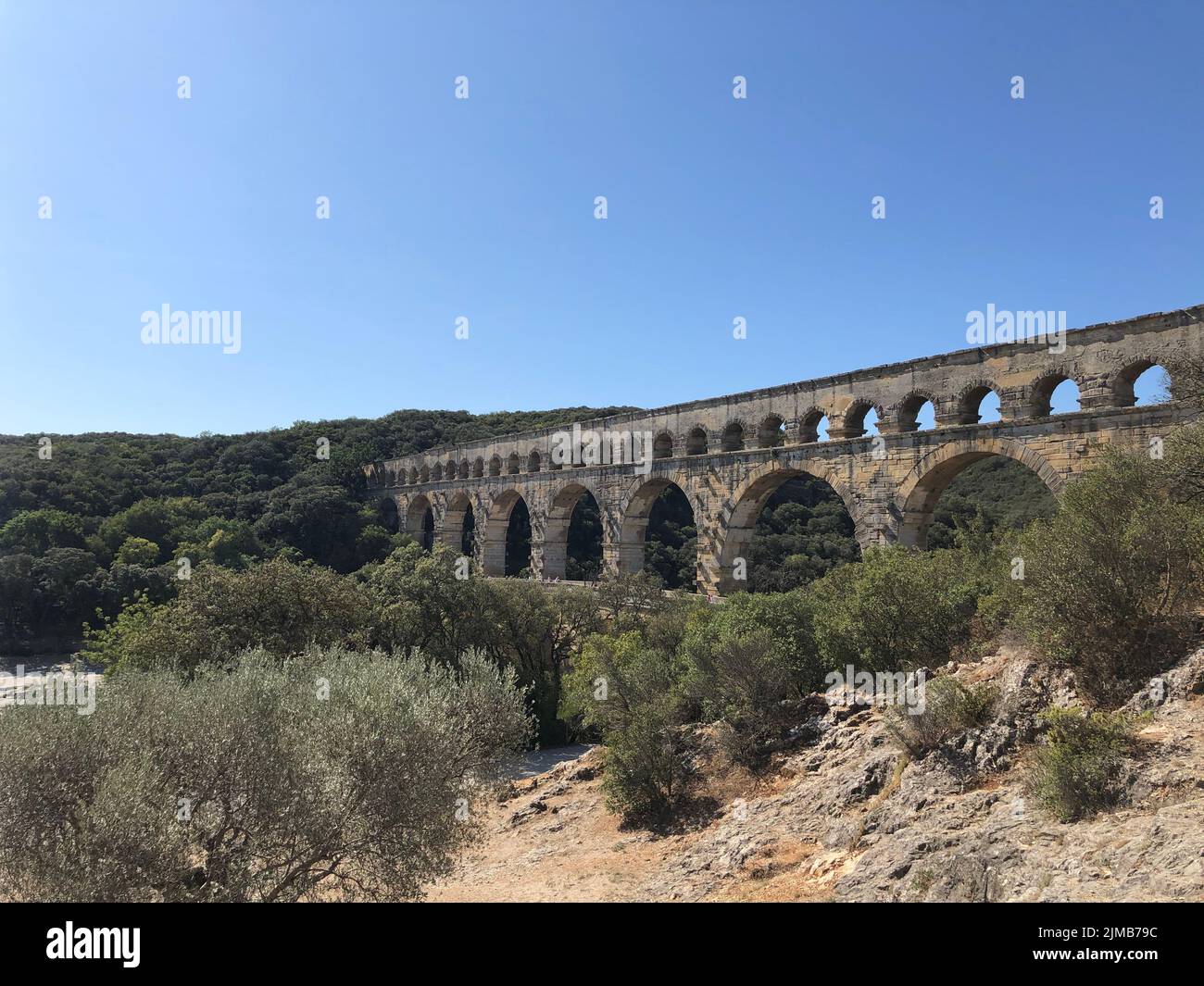 The ancient Roman arch bridge Pont du Gard surrounded by green area ...