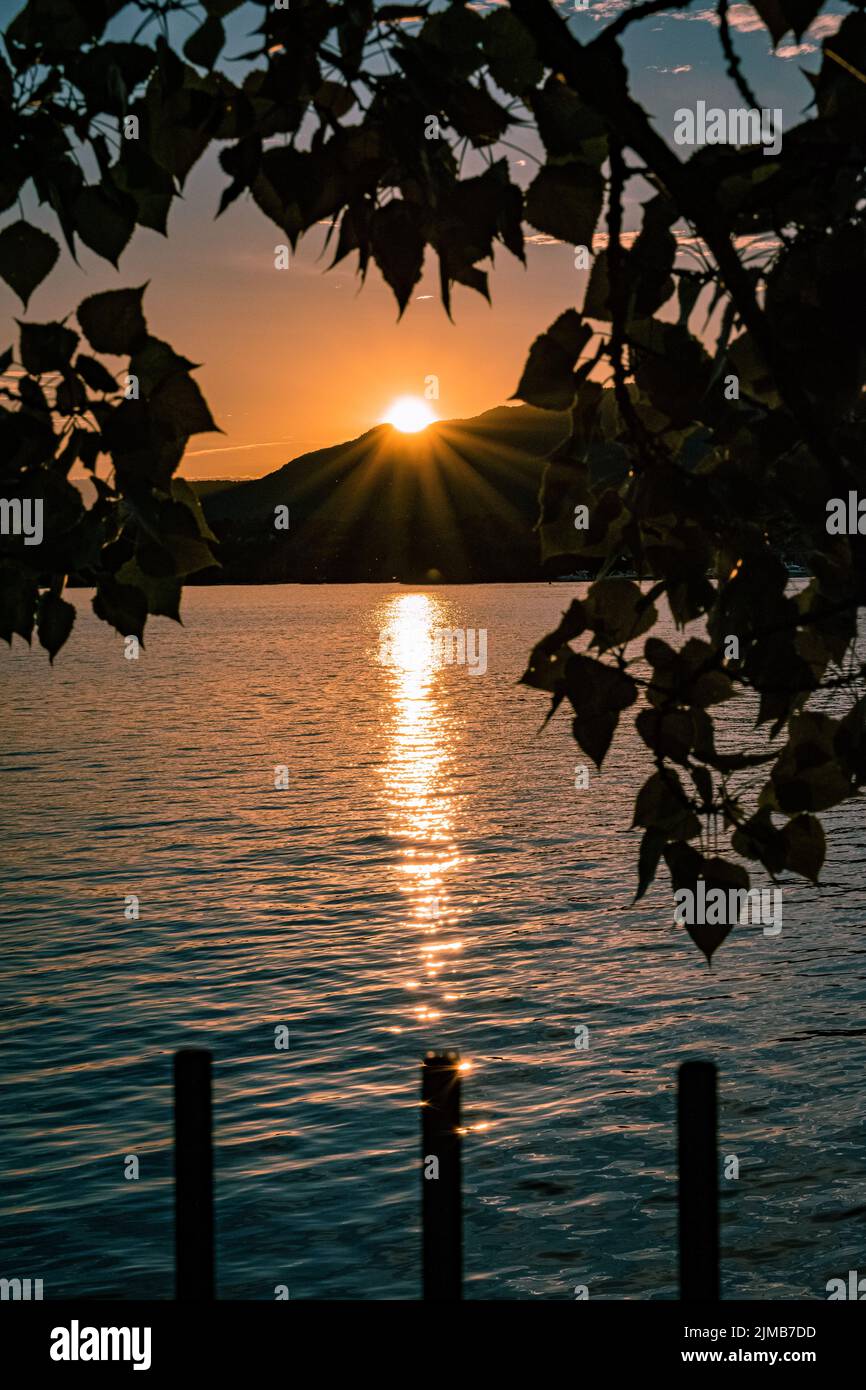 A vertical shot of the sun setting down behind a mountain over a ...