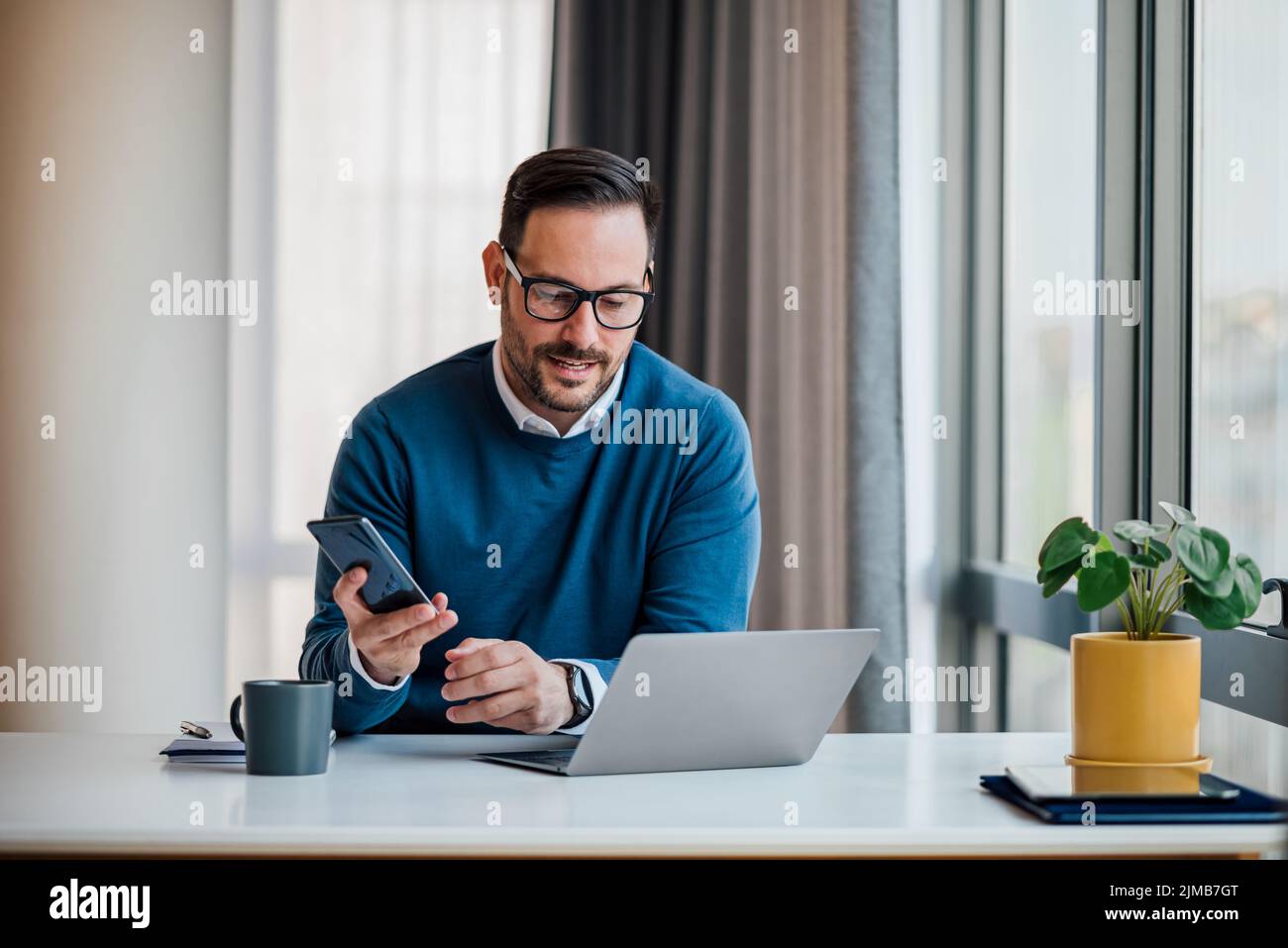 Smiling male professional using smart phone. Young businessman ...