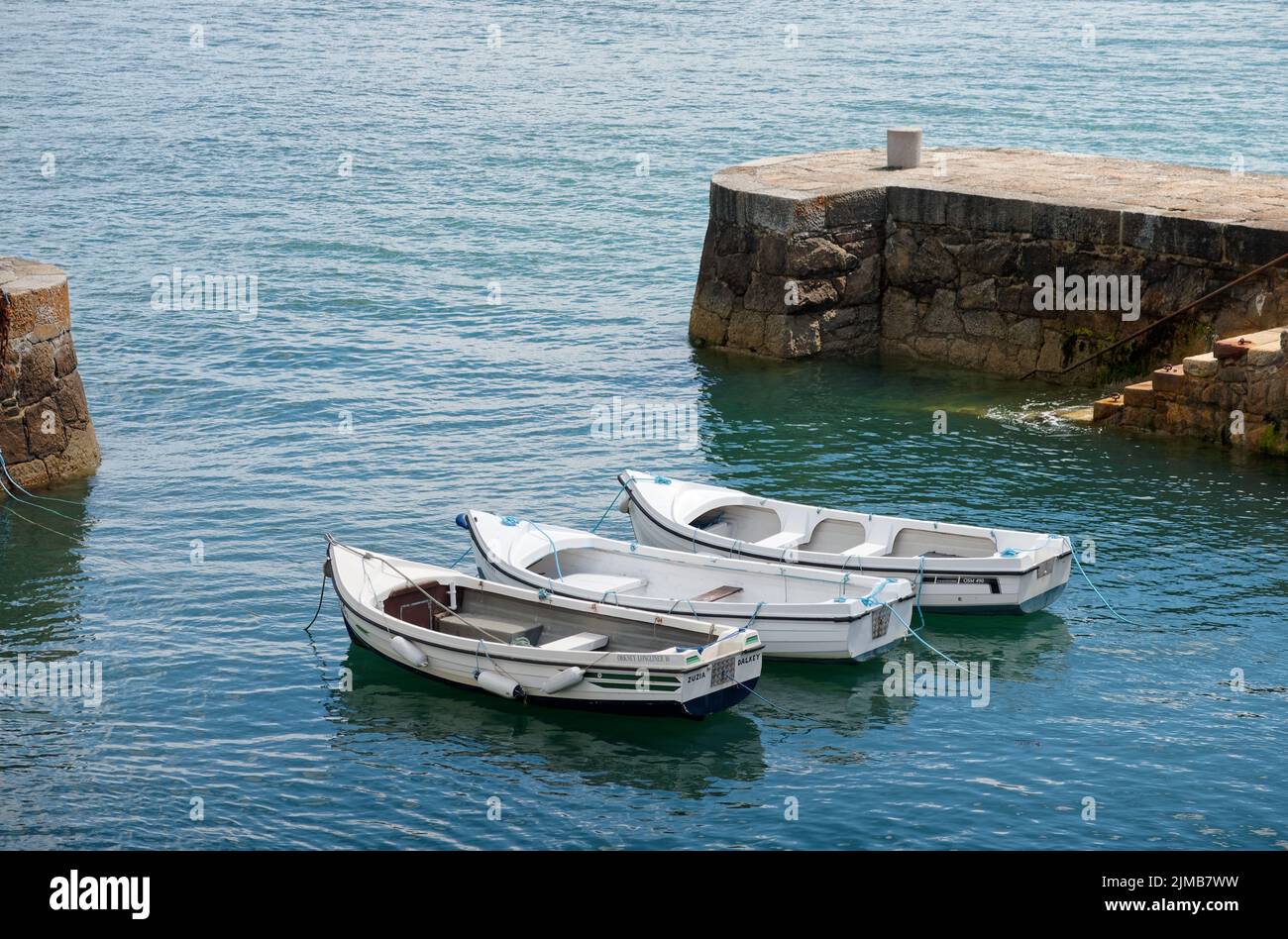 Three white boats floating in blue water moored in the Coliemore ...
