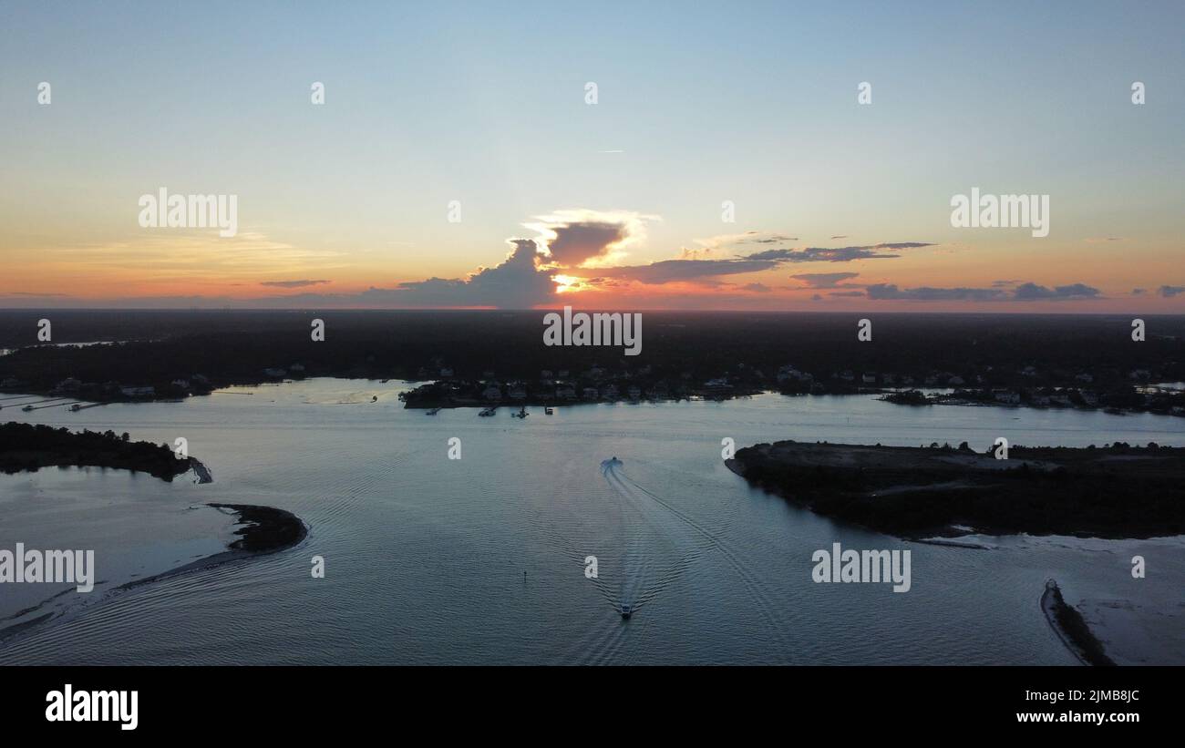 A sunset coming through the clouds as a boat passes by below Stock ...