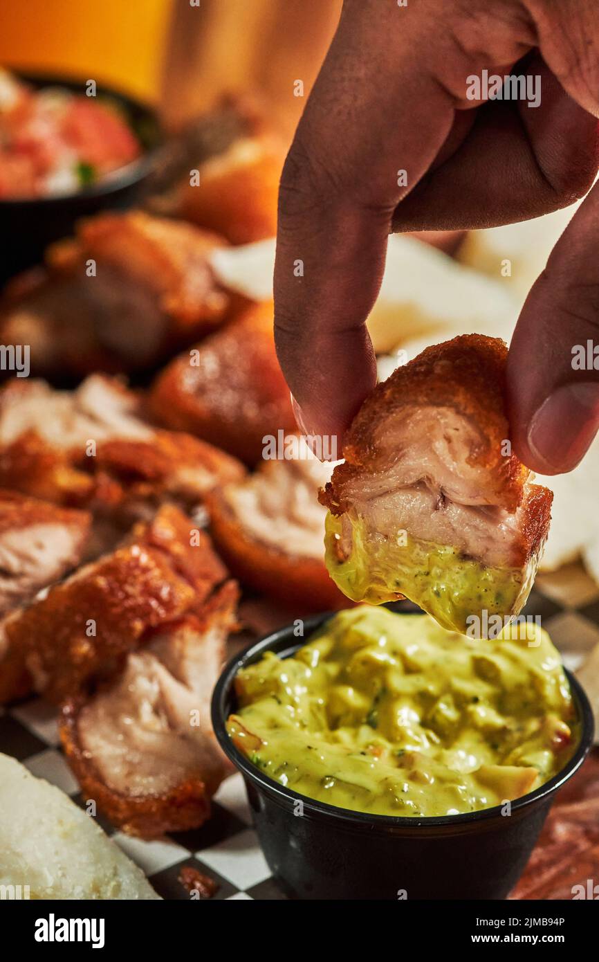 A vertical shot of a hand holding a crispy mean and Mexican sauces ...