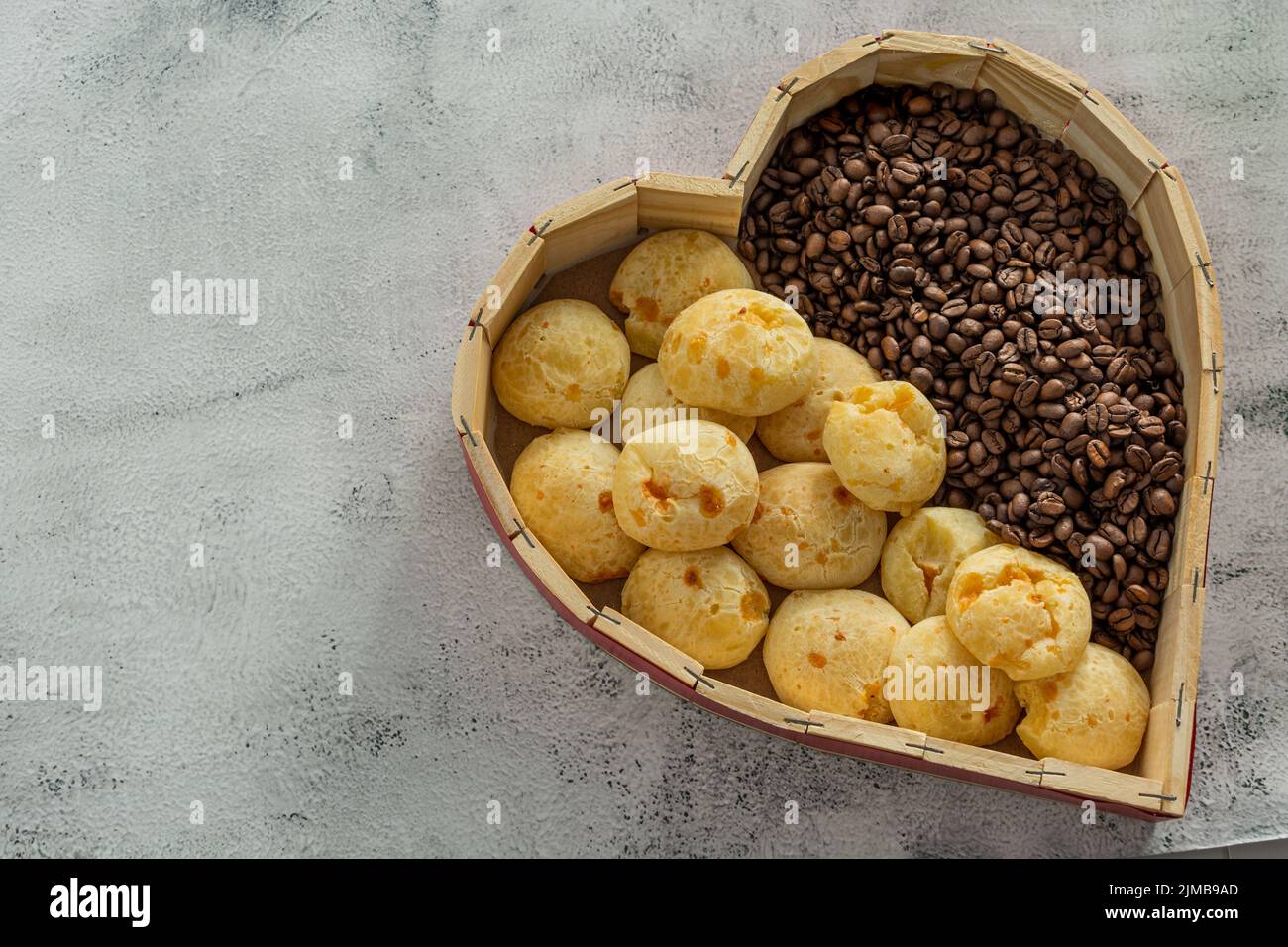 brazilian cheese bread or 'pao de queijo' in a heart shaped format basket, with coffee beans on ...