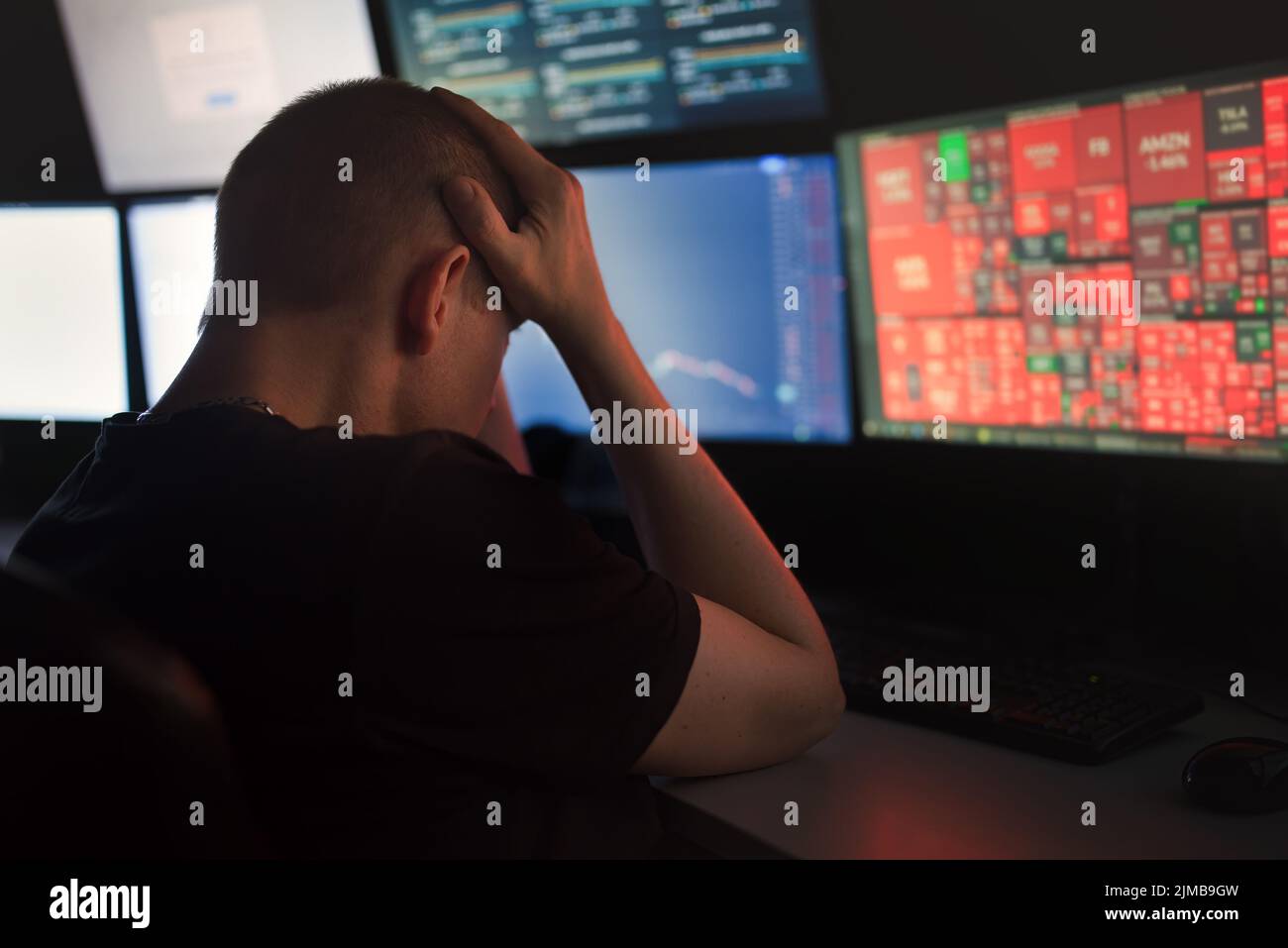 An unhappy man holding his head as he watches the stock market plunge ...