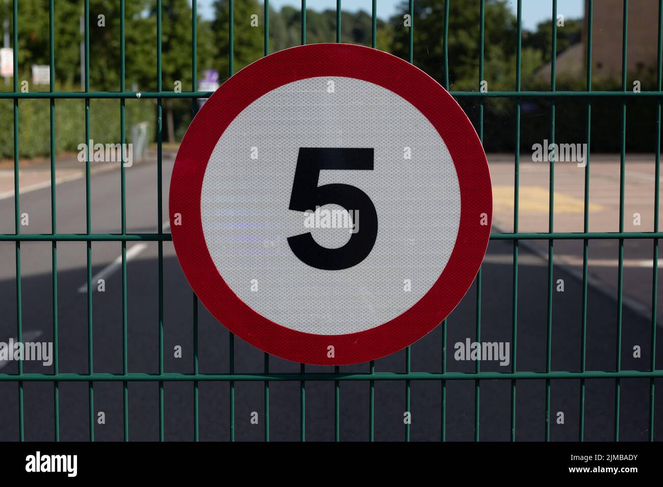 A closeup front view of a "speed limit is 5" sign on a green metal ...