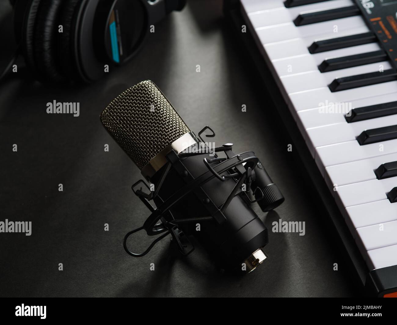 Studio microphone, headphones and a modern synthesizer-midi keyboard on ...