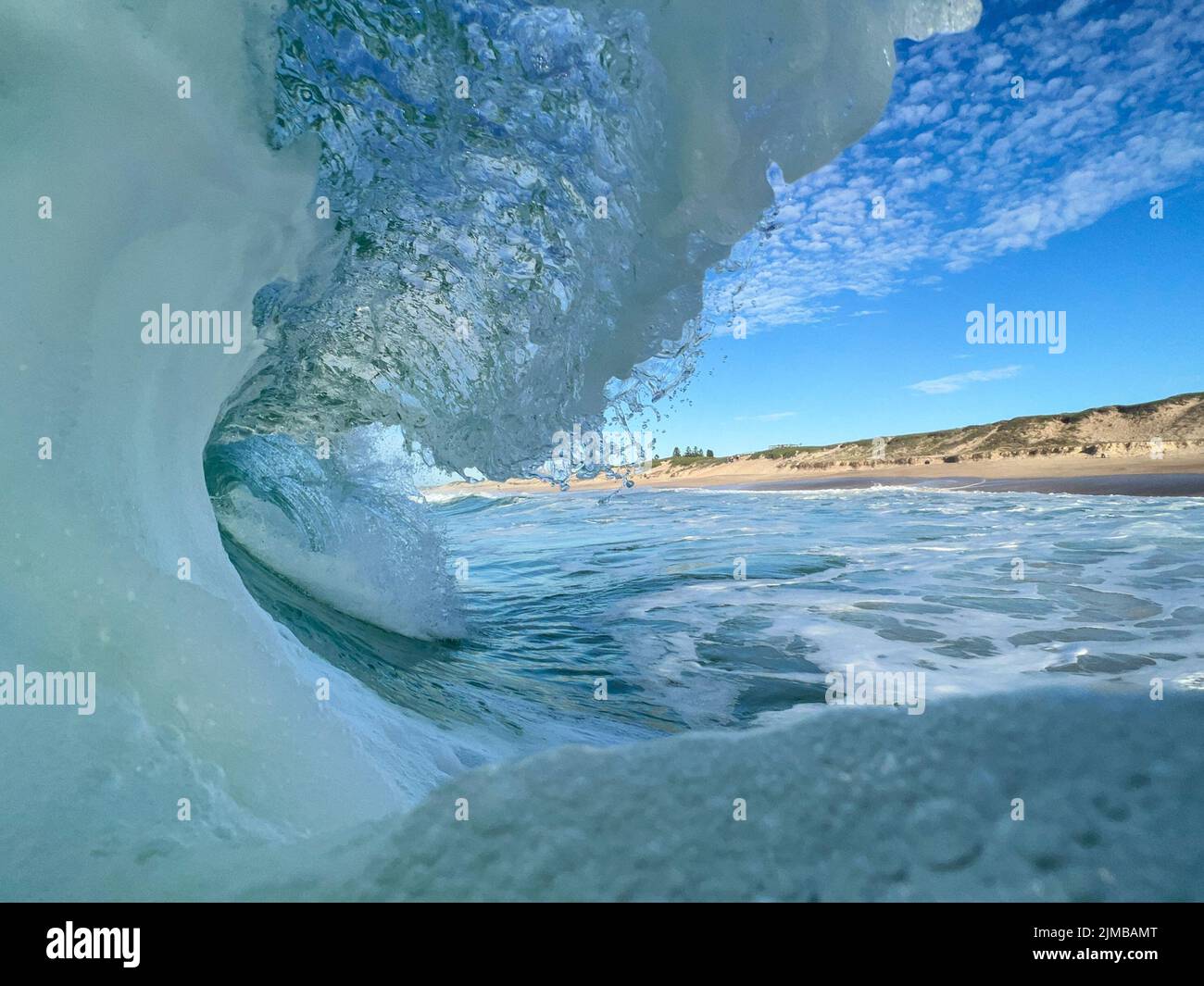 O closeup shot of a foamy ocean wave forming a tube during the daytime ...