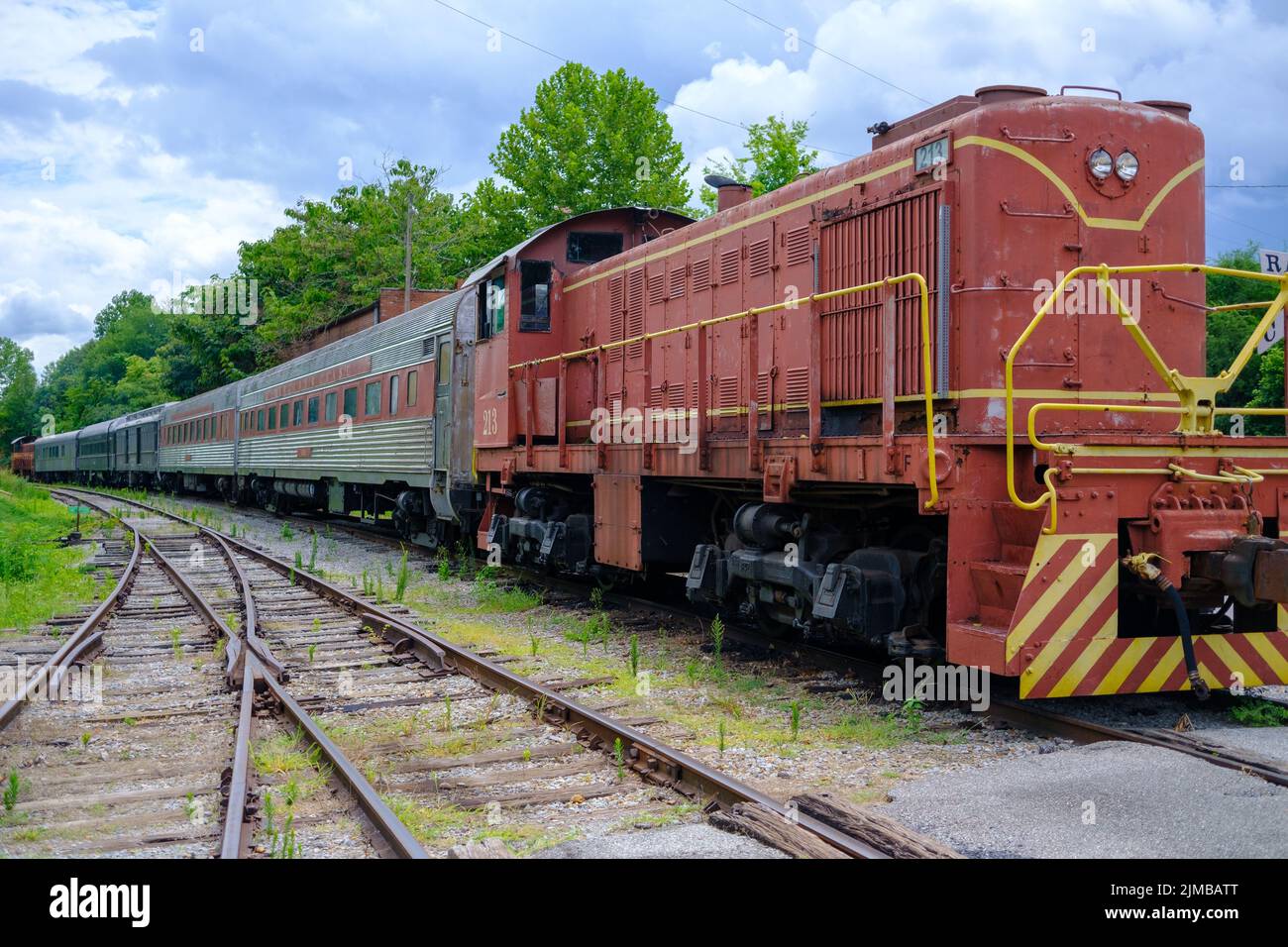 A closeup of an old red train standing on the tracks surrounded by ...