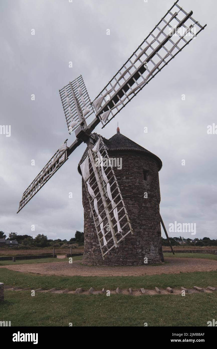 A vertical shot of a old big windmill with a gloomy sky on the horizon ...