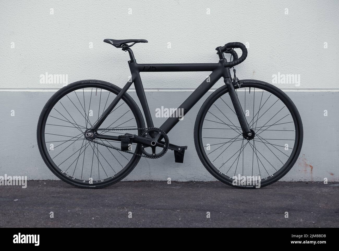 An all-black race bicycle on the street leaned on a white wall Stock ...
