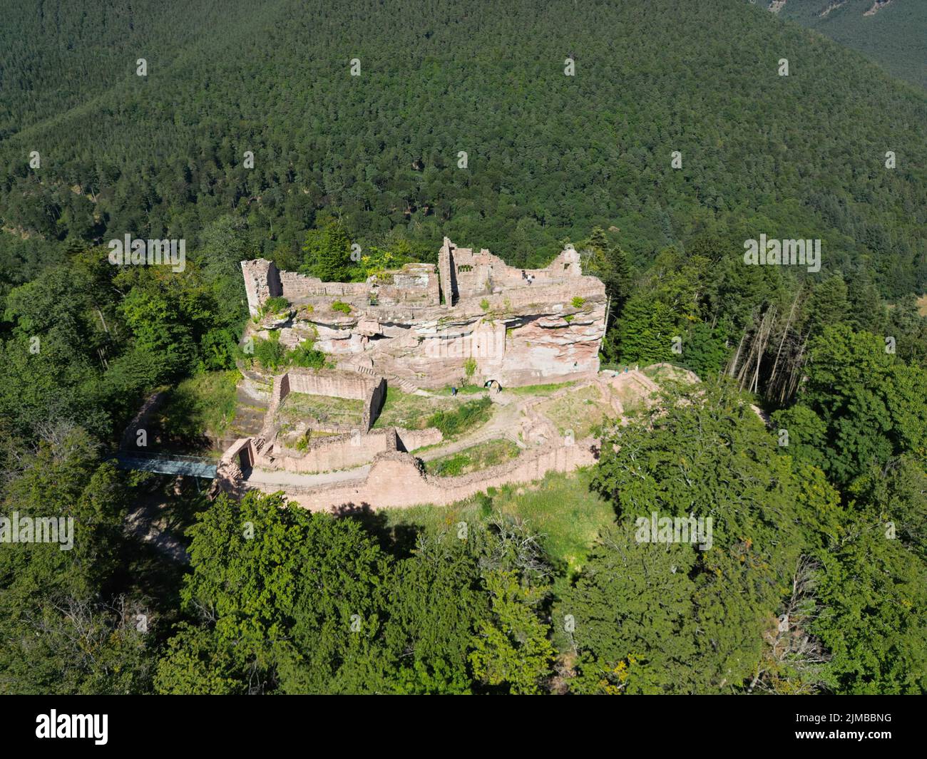 An aerial view of a ruined old building in a forest surrounded by green ...