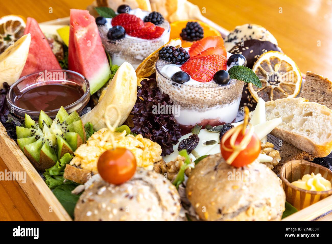 A closeup of assorted fruits, cheese, bread, and dessert on a platter ...