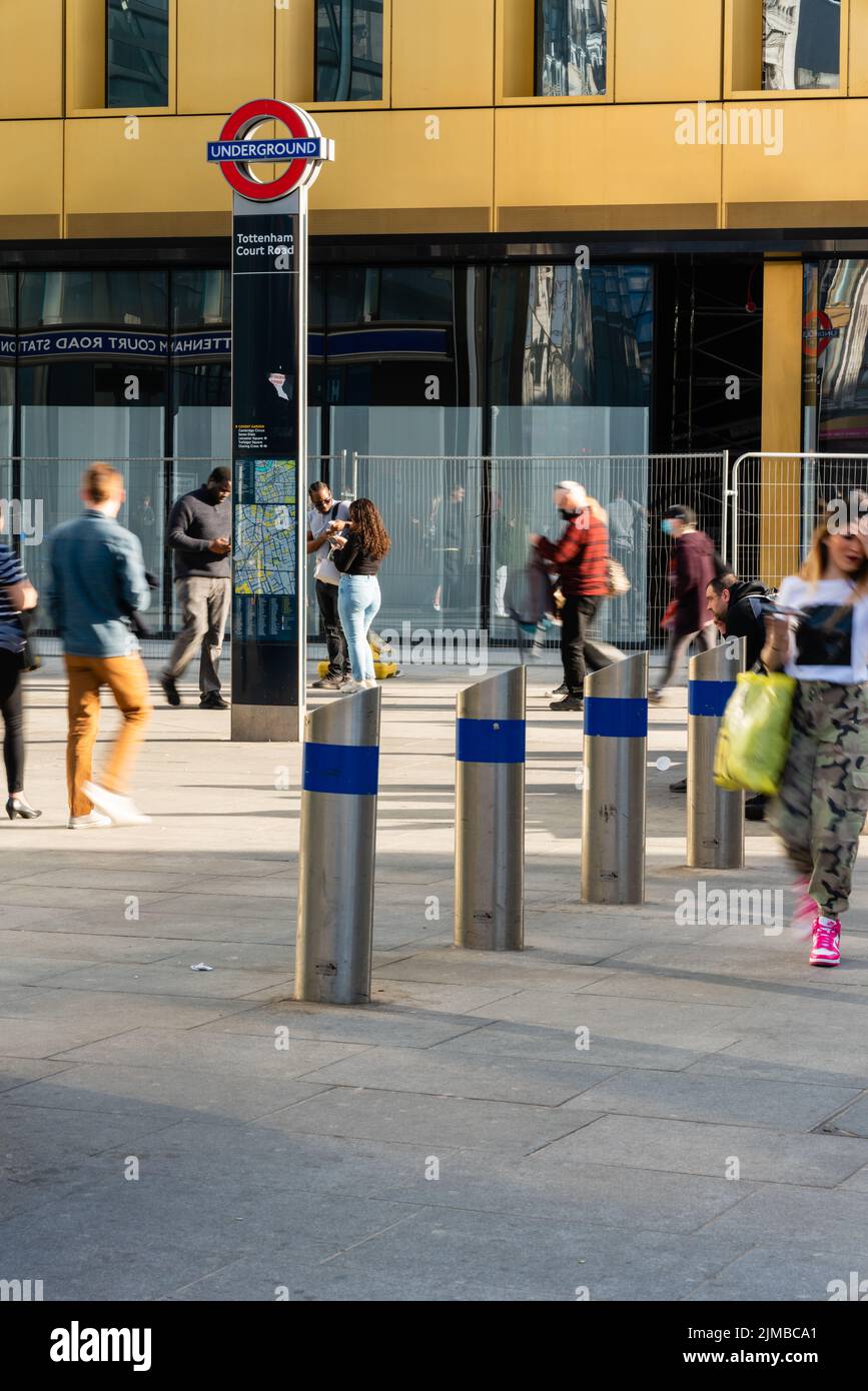 a vertical shot of busy commuters walking around a pillar sign for ...