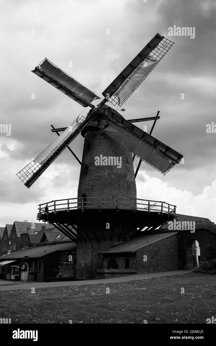 A vertical grayscale of an old windmill against a cloudy sky Stock ...