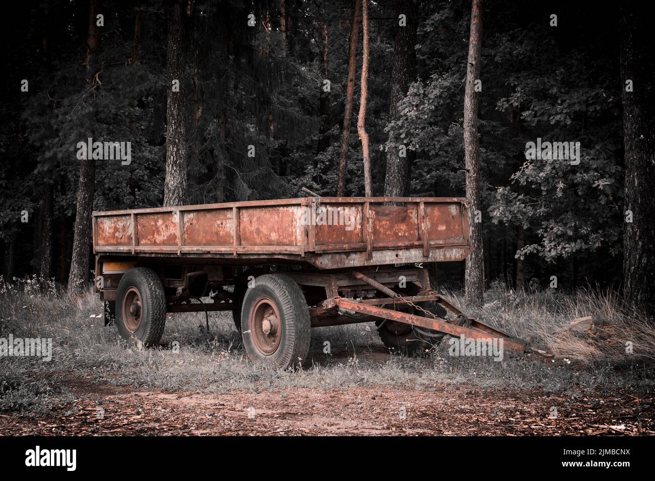 A view of a rusty trailer in a field with trees Stock Photo - Alamy