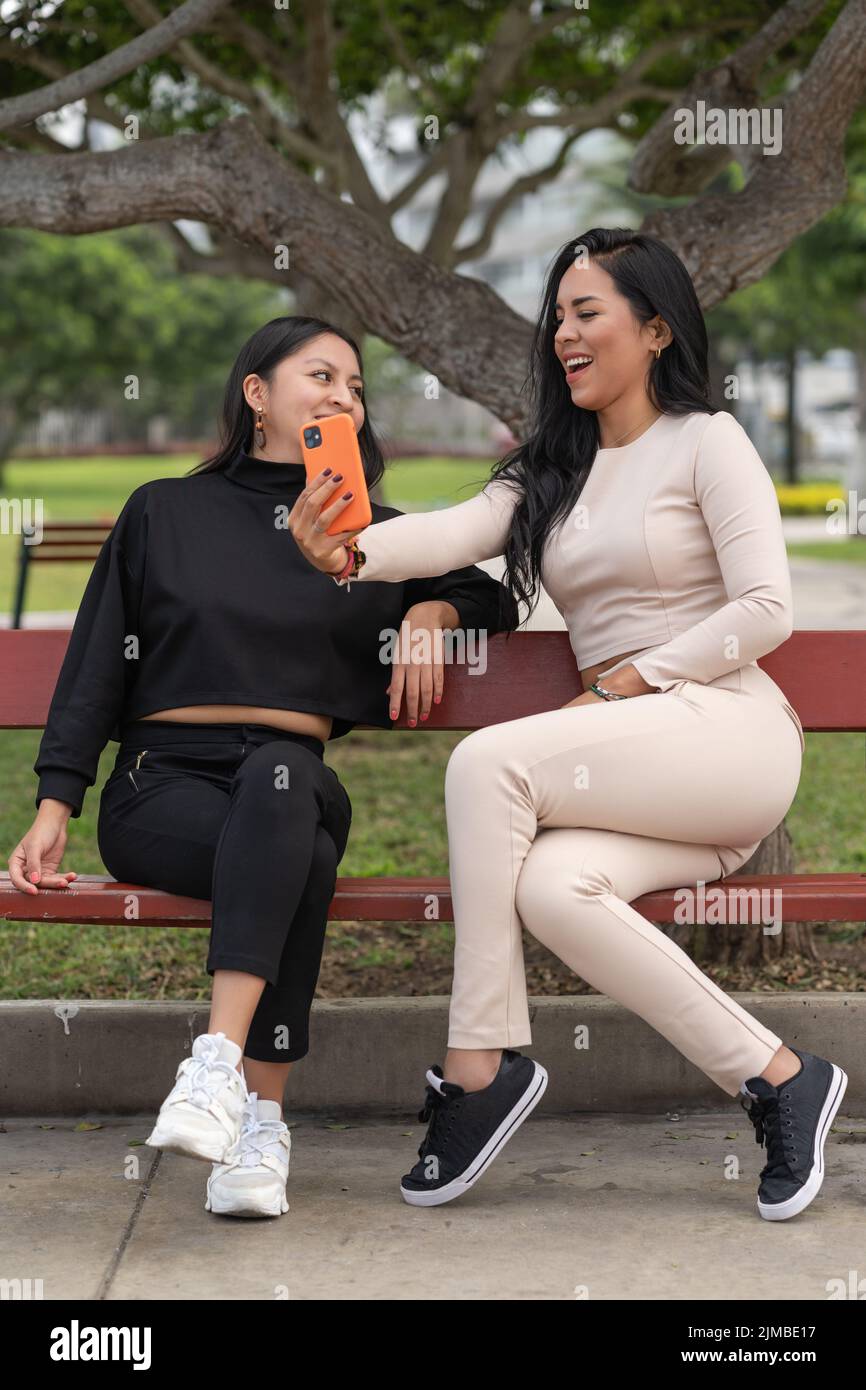 Vertical photo of two woman taking a selfie with mobile Stock Photo - Alamy
