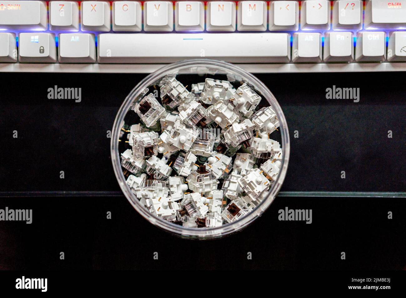 A top view of mechanical keyboard switches piled in a transparent jar ...