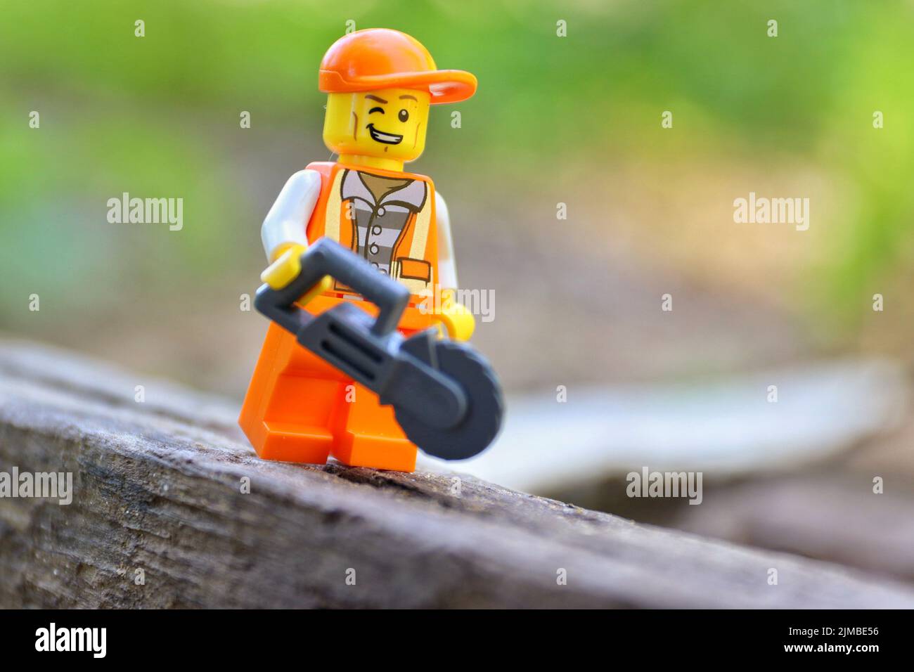 Toy construction worker, smiling and holding a chain saw, happy to ...