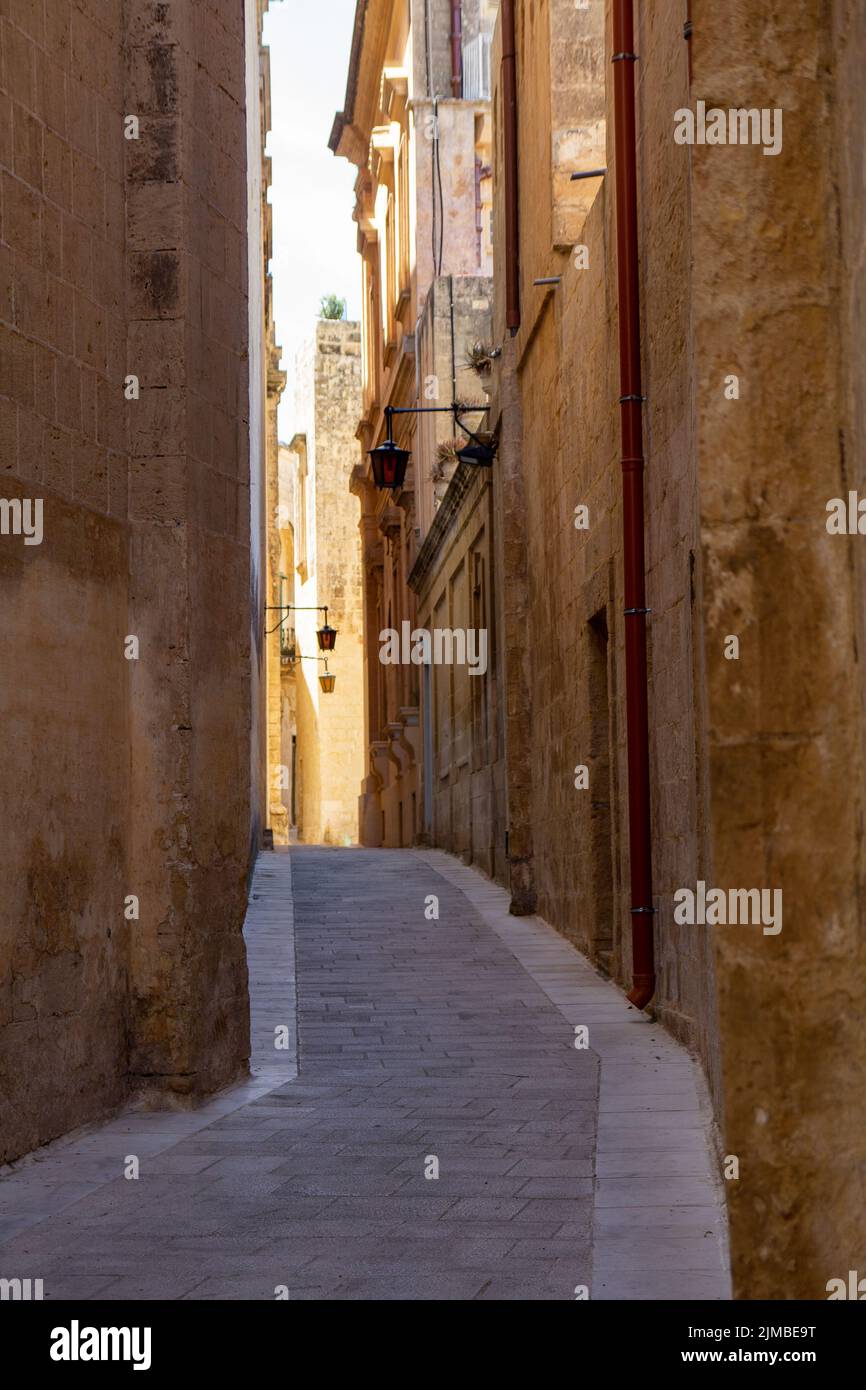 A vertical shot of narrow alley between stone buildings in Malta Stock ...