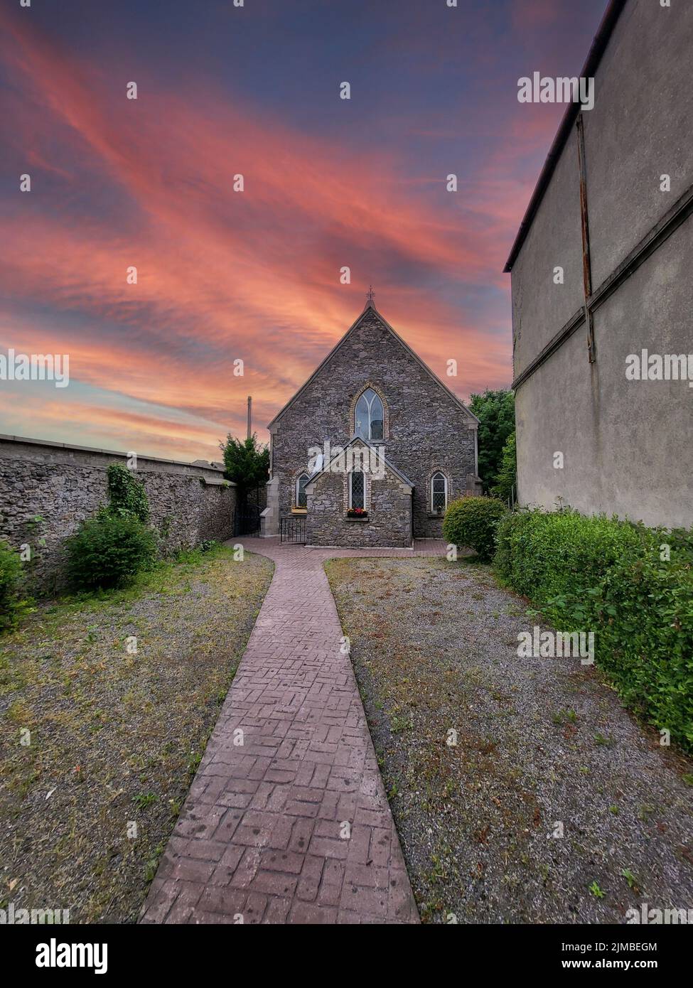 A path leading to the stone church with pink sunset background, a ...