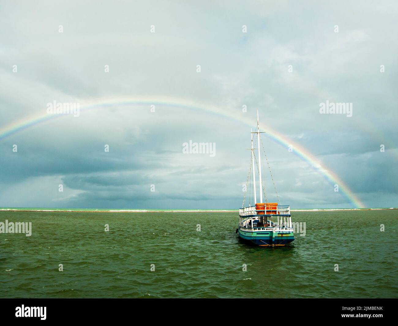 The boat sailing on the green sea with a beautiful rainbow in the ...
